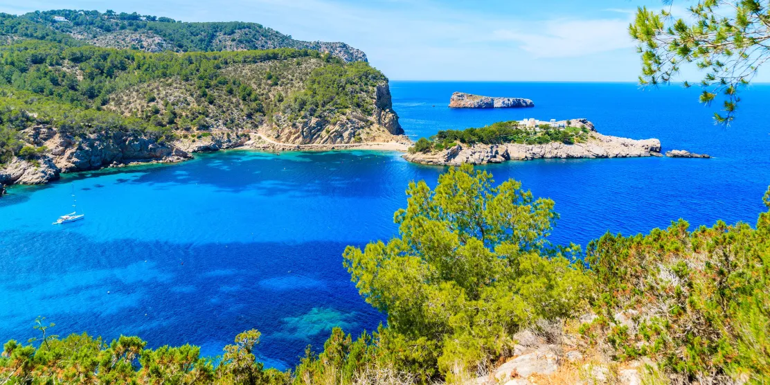 Blue bay and green hills on the coast of Ibiza, Spain.