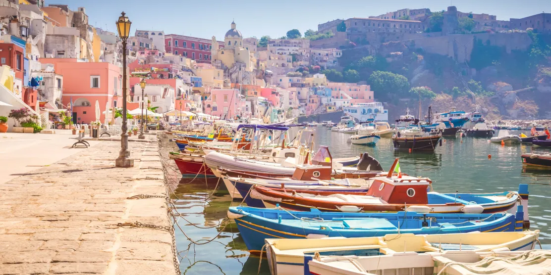 Colorful pastel houses and fishing boats in a harbor near Ischia, Italy.
