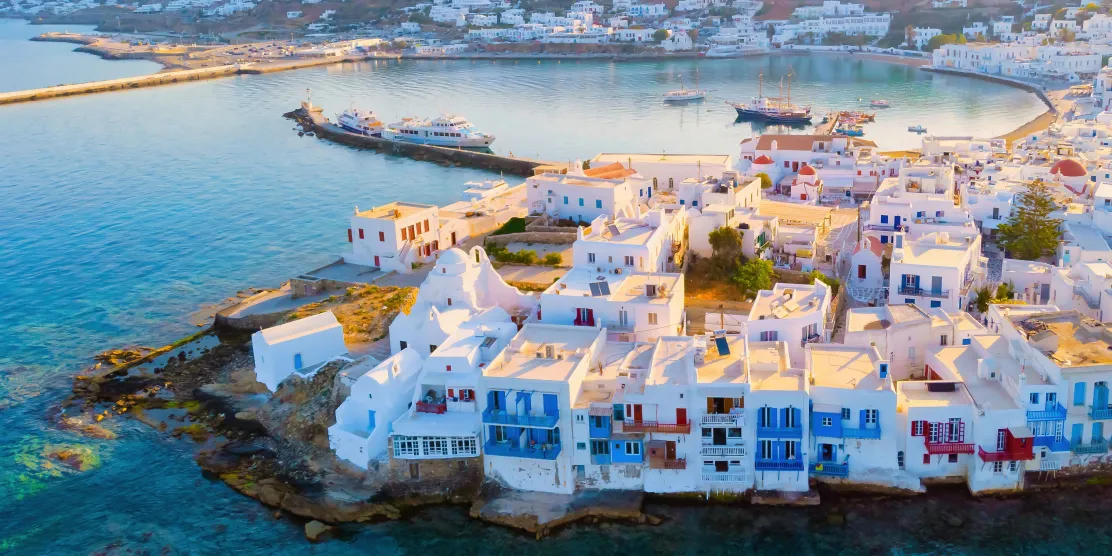 White-washed village and blue domes on the coast of Mykonos, Greece.