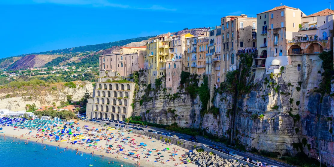 Steep cliffs and historic buildings above the beach in Tropea, Italy.