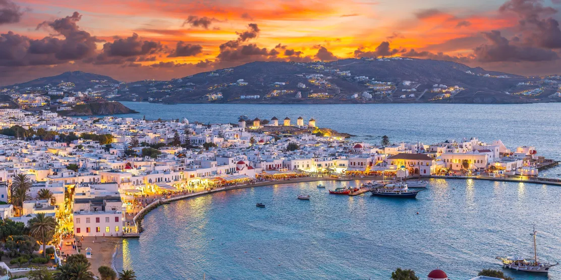 Coastal Greek town panorama and windmills at sunset