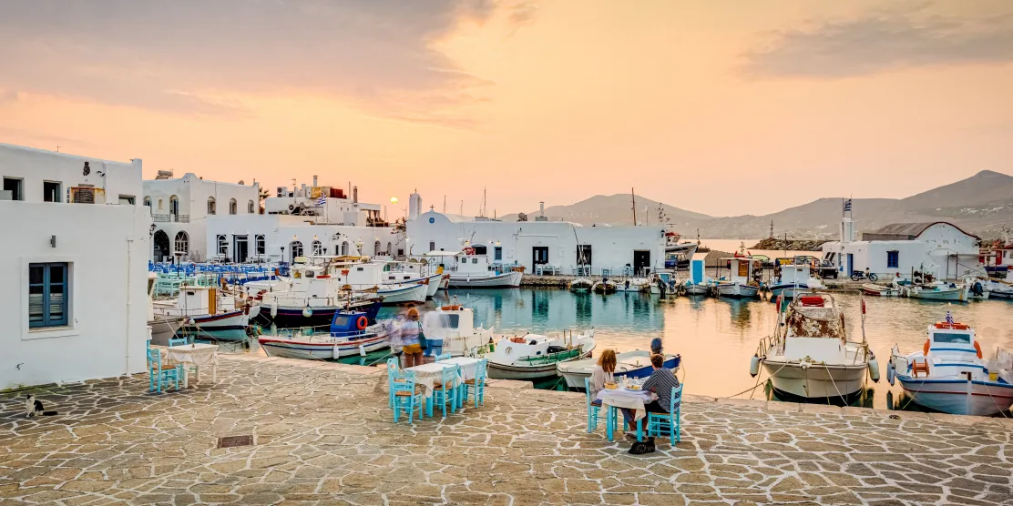 Waterfront dining with blue chairs at a harbor on a Greek island