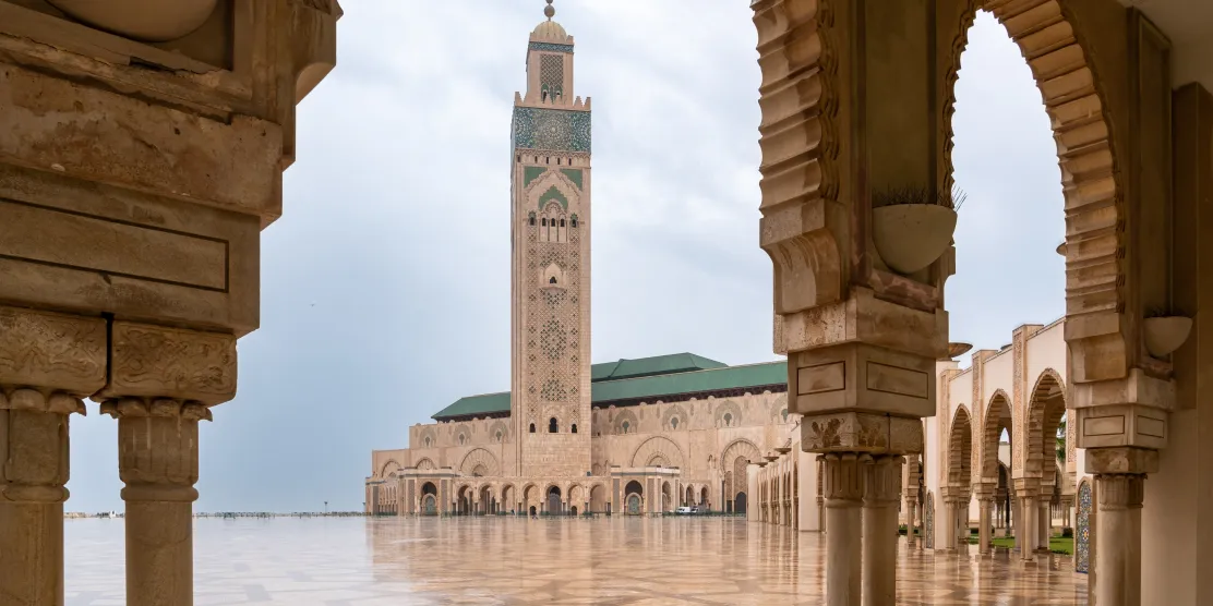 Hassan II Mosque and minaret framed by stone arches.