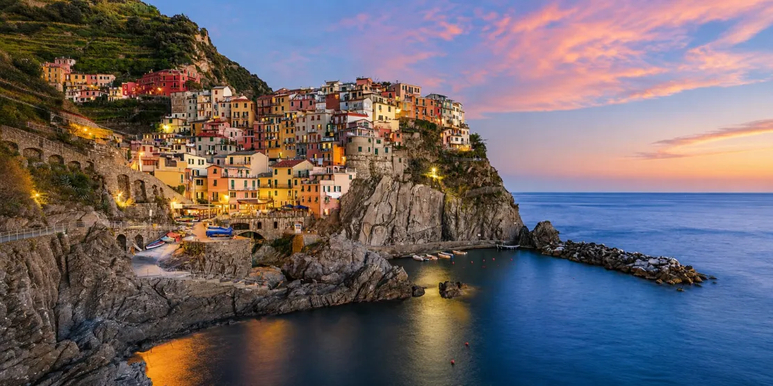 Cinque Terre hiking trail showing the colorful coastal village of Manarola on a steep cliff at sunset.