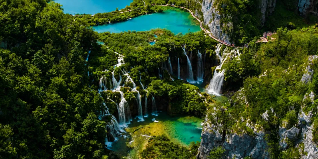 Plitvice Lakes national park trail with an aerial view of cascading waterfalls and crystal-clear turquoise lakes.