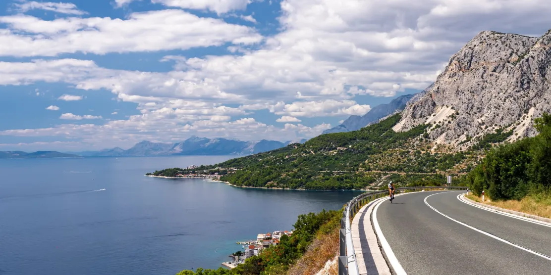 Dalmatian Coast road trip route in Croatia, with a scenic coastal road overlooking the Adriatic Sea and mountains