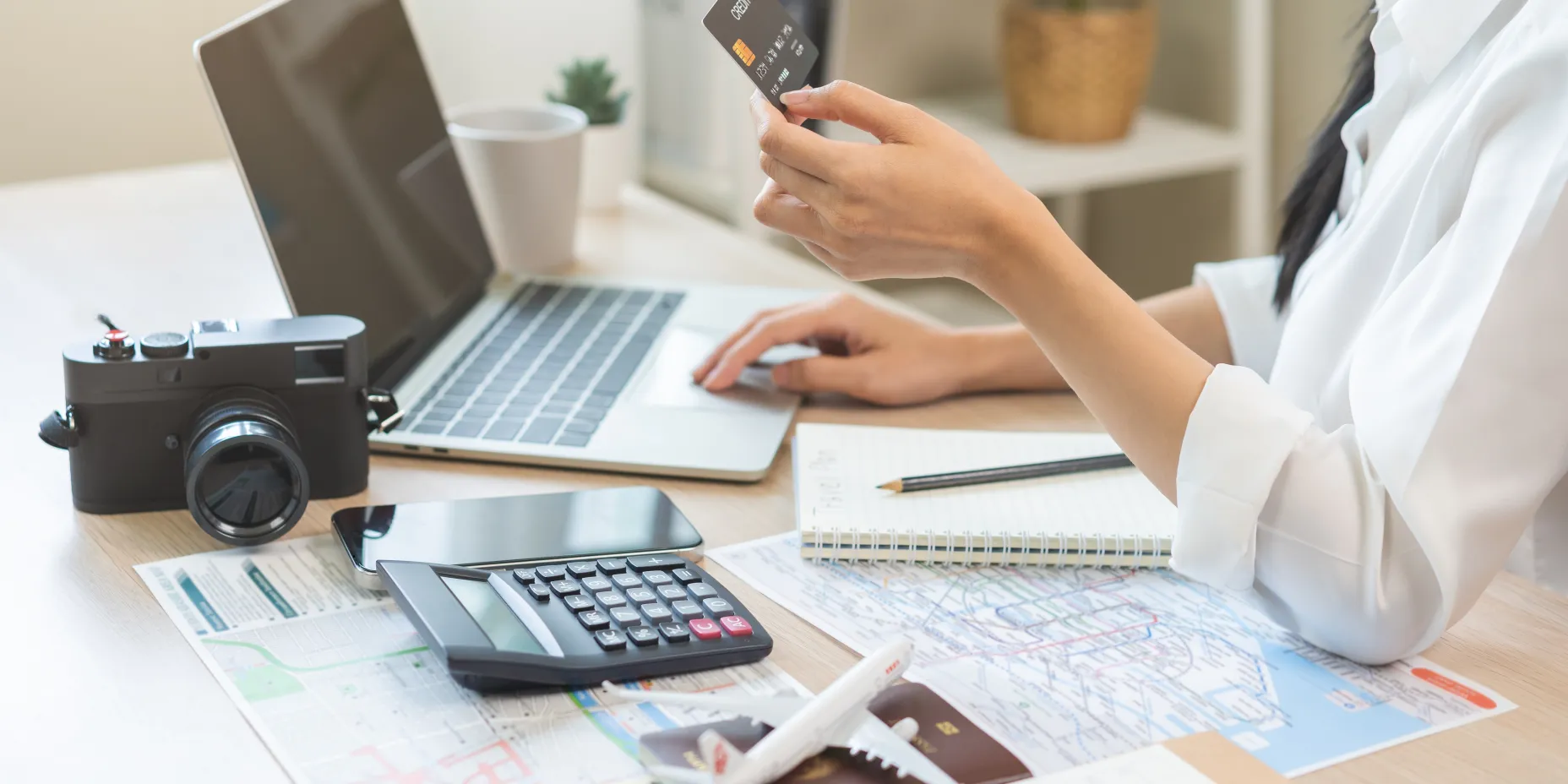 Femme réservant un voyage en ligne, carte bancaire en main.