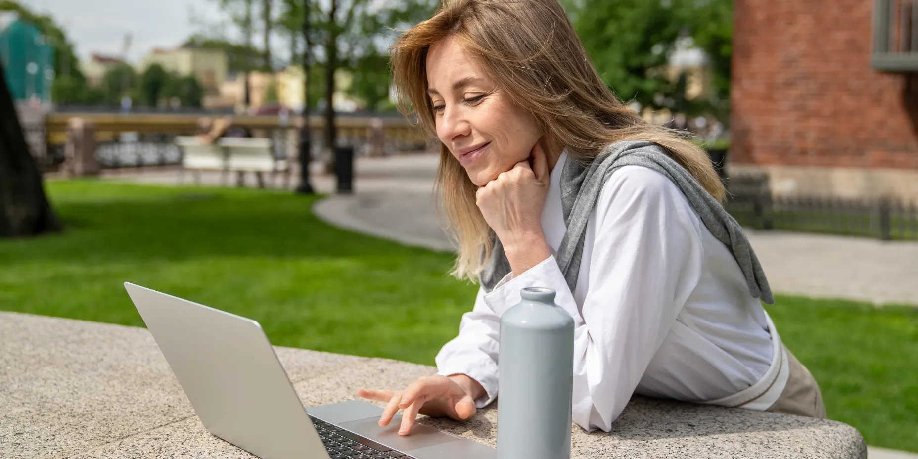 Woman browsing on laptop outside.