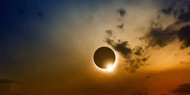 Total solar eclipse with diamond ring effect in a twilight sky.